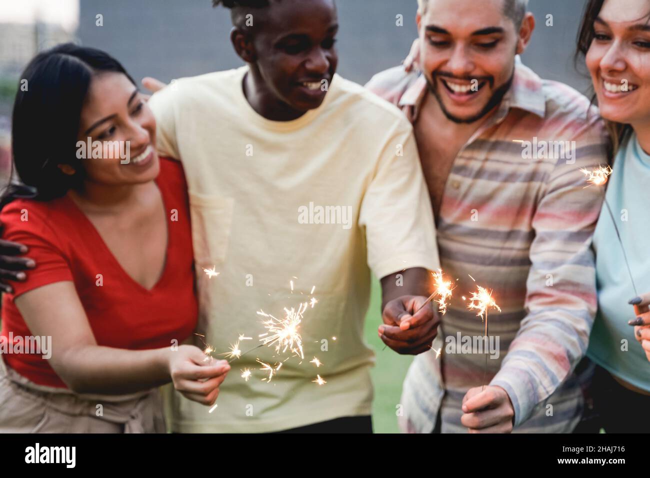 Diverse friends having fun celebrating with fireworks - Focus on ...