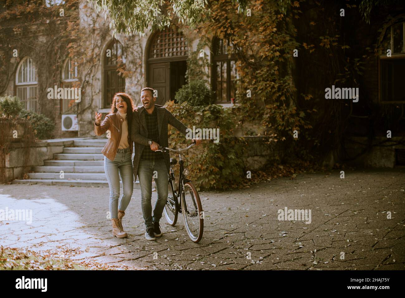 Handsome young couple walking with bicycle in autumn park Stock Photo ...