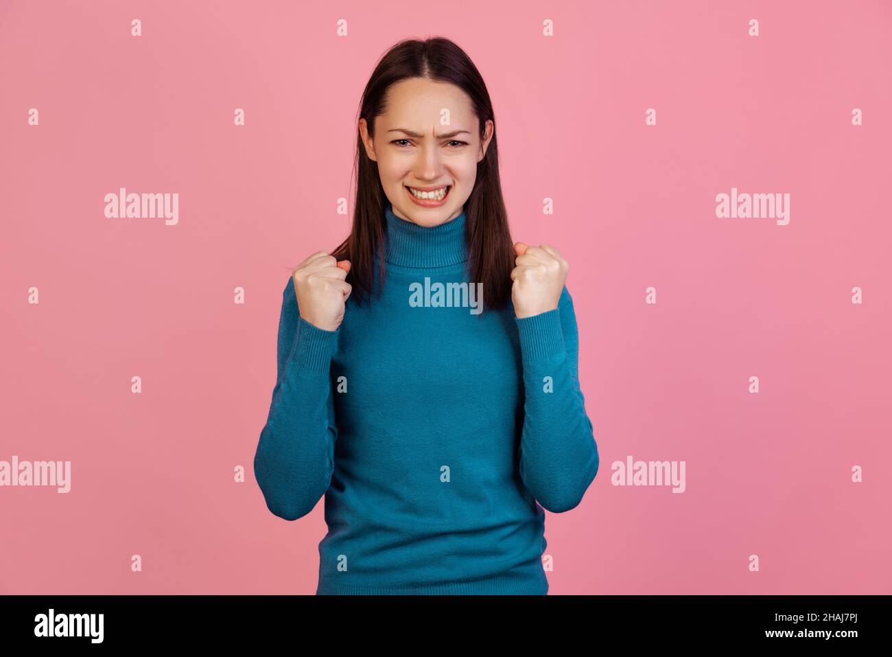 One emotive young girl in warm winter blue sweater isolated on pink ...