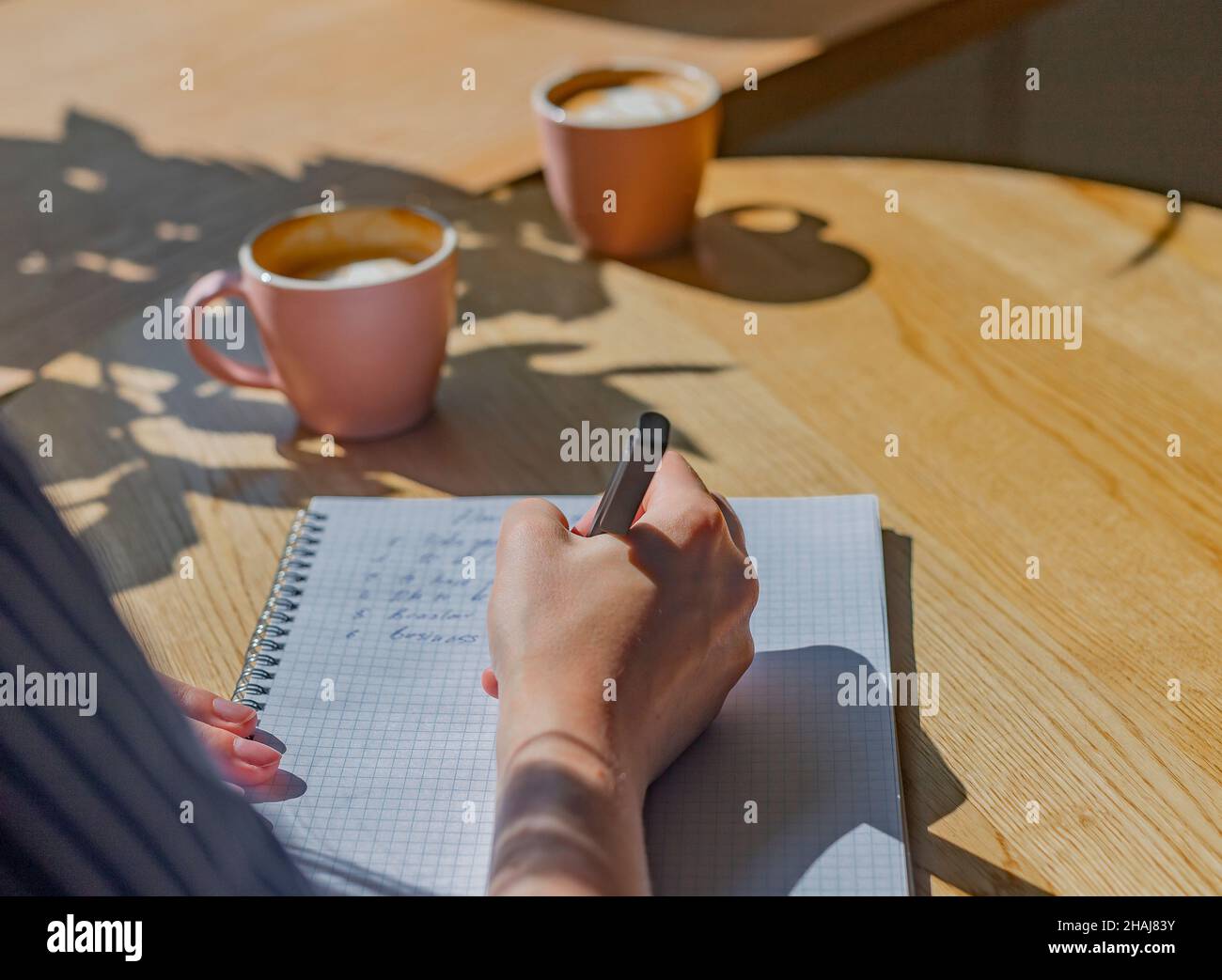 Women hand writing plans in notebook or planner over wooden cafe table ...