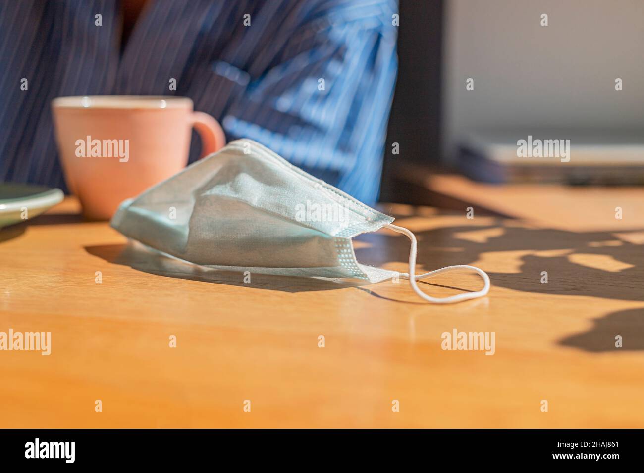 Coffee cup and face mask on wood table in cafe Stock Photo - Alamy