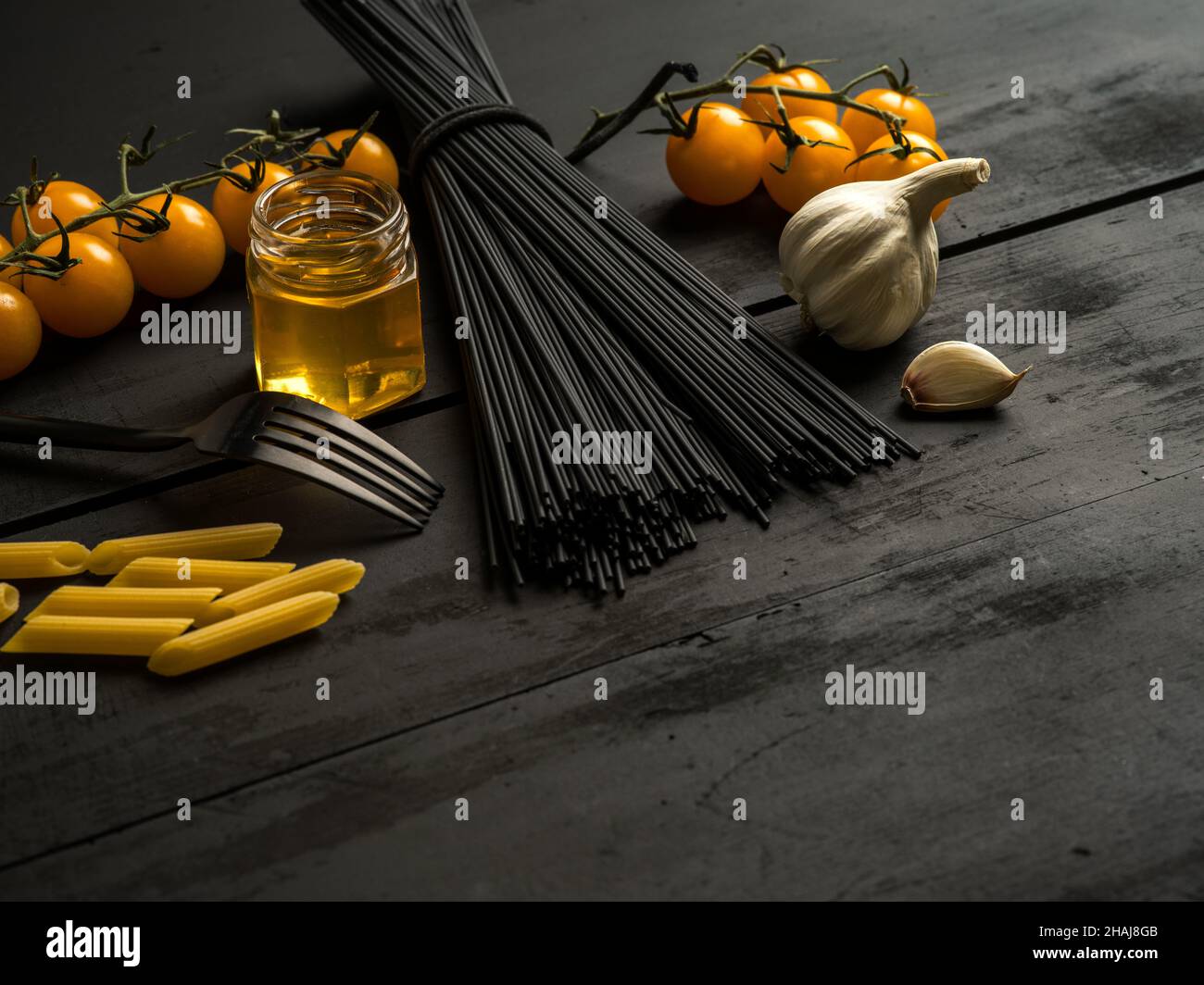 Pasta ingredients over a black wood background Stock Photo - Alamy