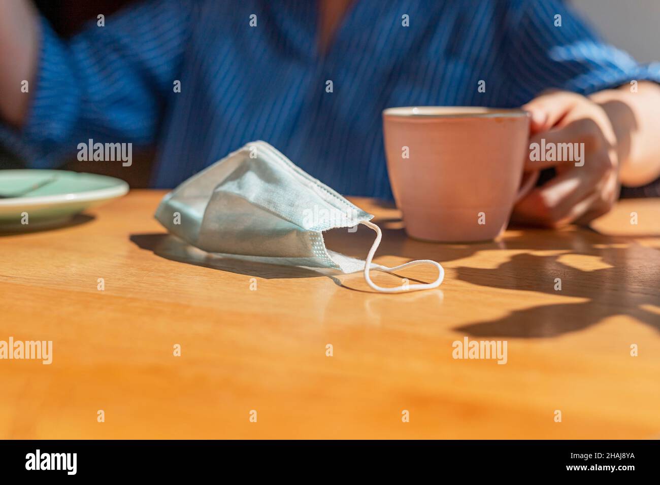 Coffee cup and face mask on wood table in cafe. New normal concept ...