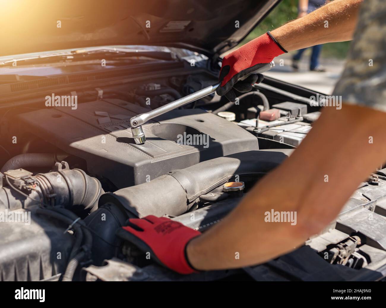 Man in gloves repairing and fixing car with wrench and open hood up ...