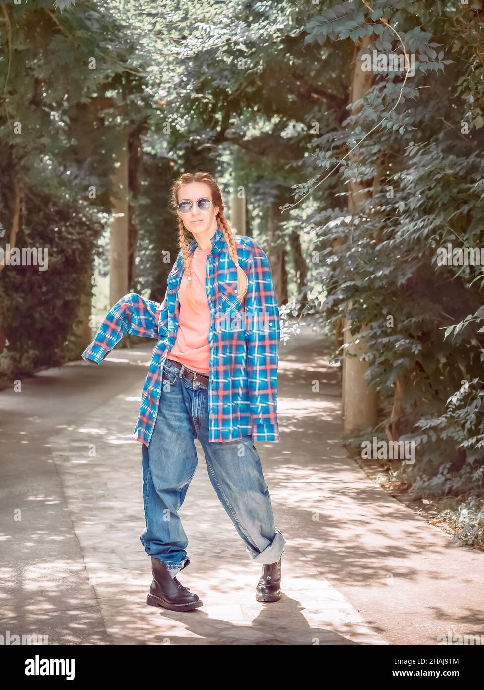 A girl with two pigtails in plaid shirt with oversleeves and oversized ...