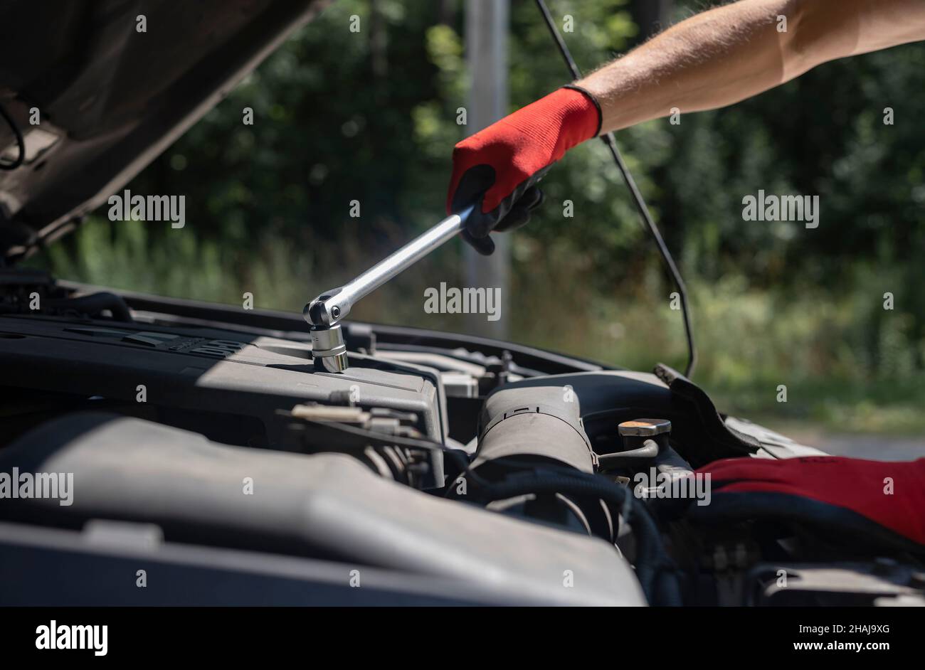 Repairman repairing car engine with wrench and open hood in nature ...