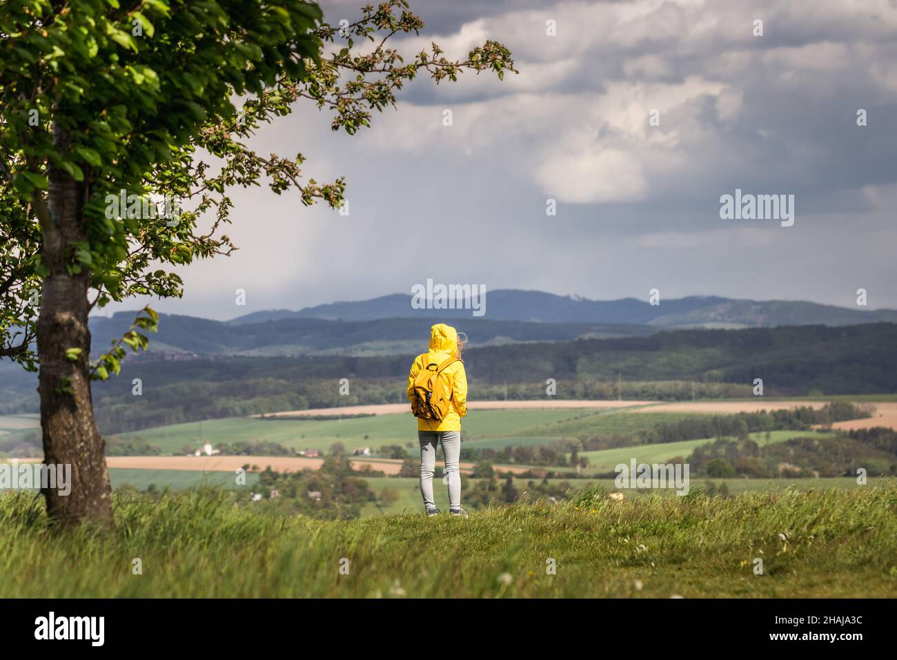Woman standing in wind during hike at springtime. Storm and rain is ...