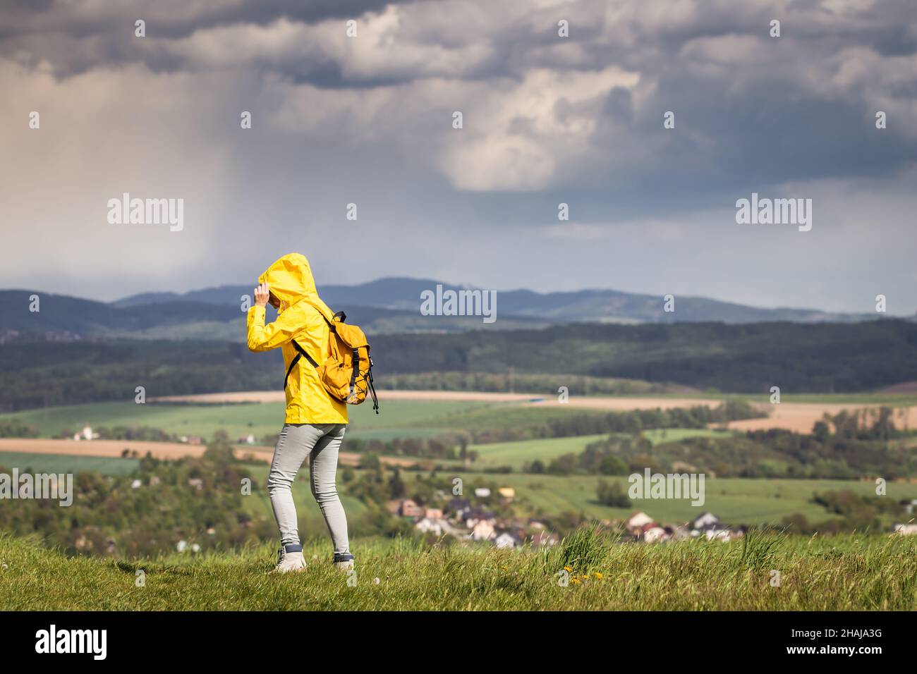 Storm and rain is coming. Tourist is wearing waterproof jacket with ...