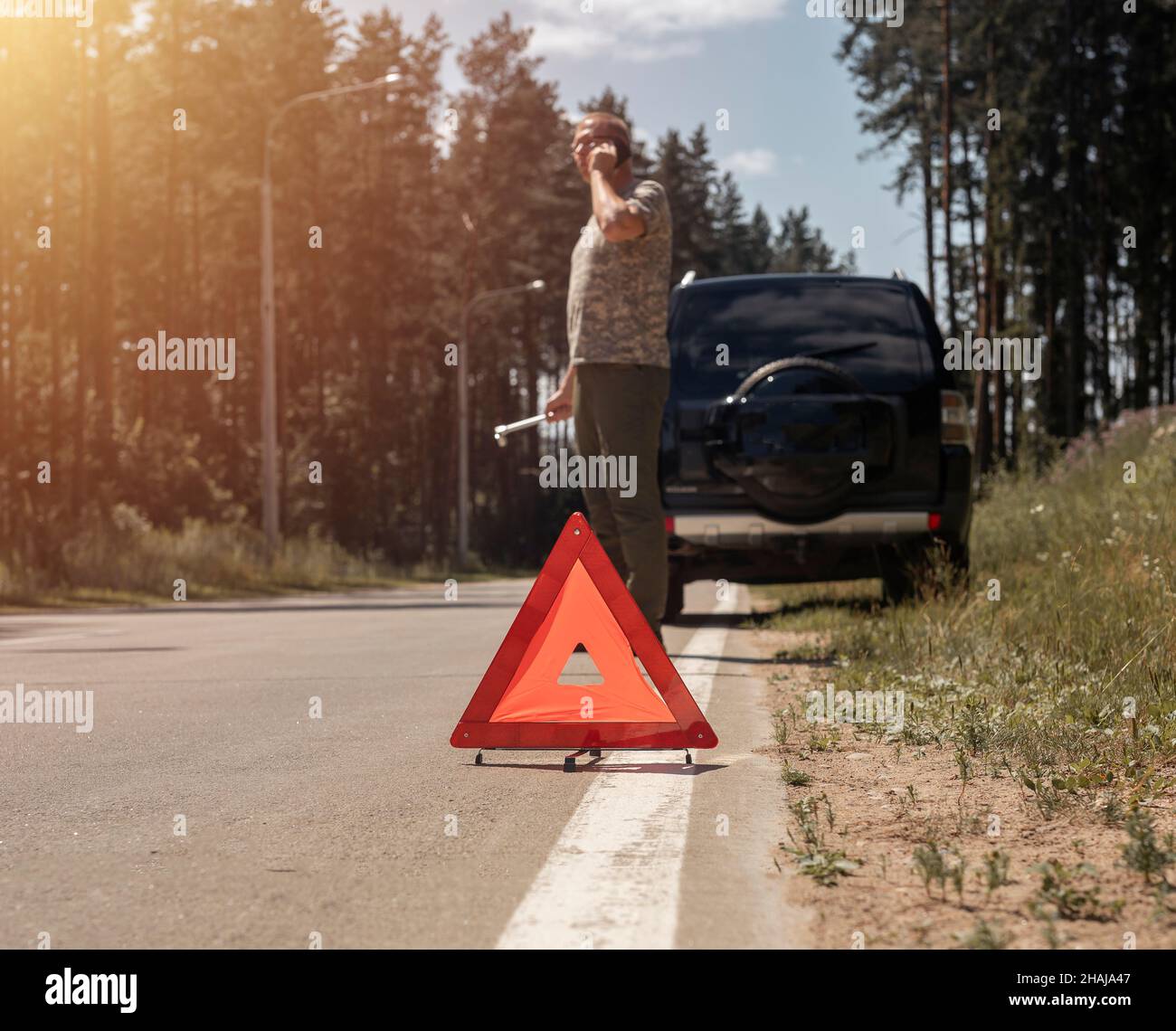 Triangle caution warning sign on road side after car break and driver ...