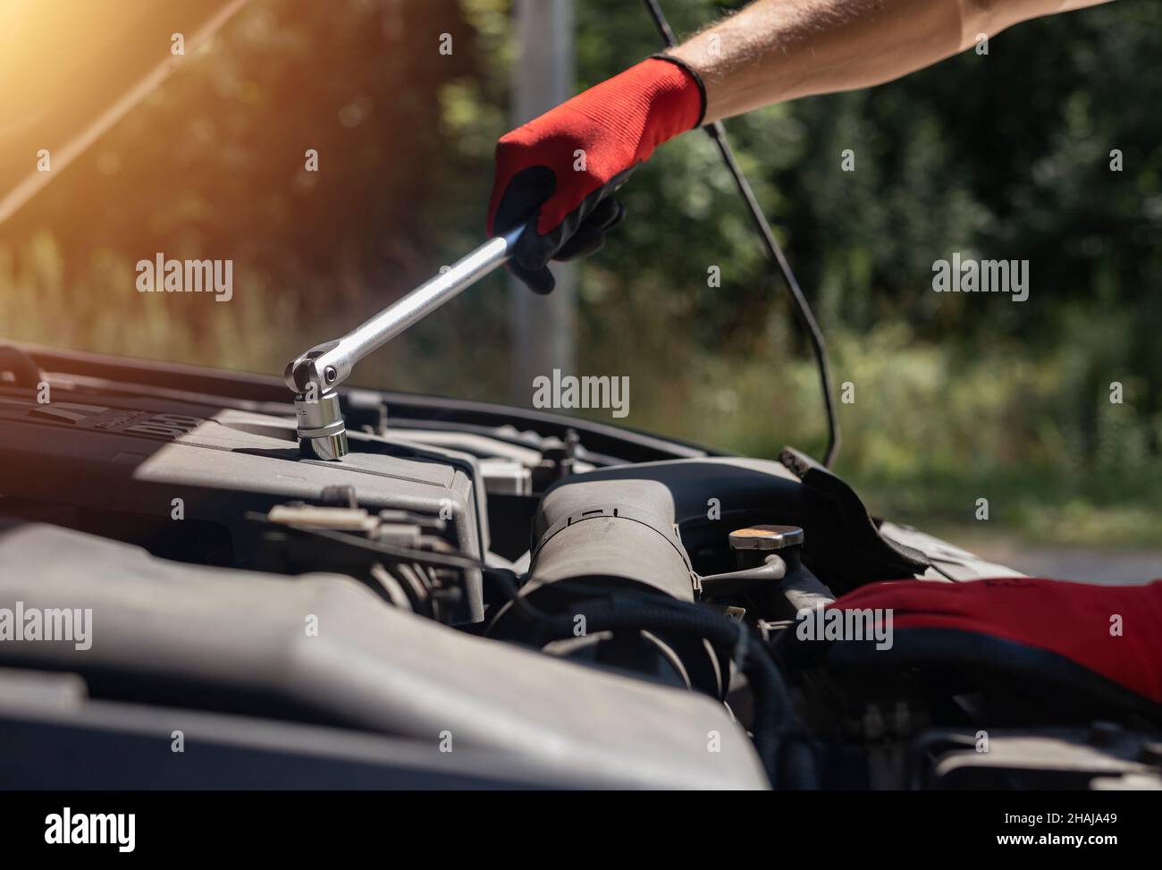 Repairman repairing car engine with wrench and open hood in nature ...