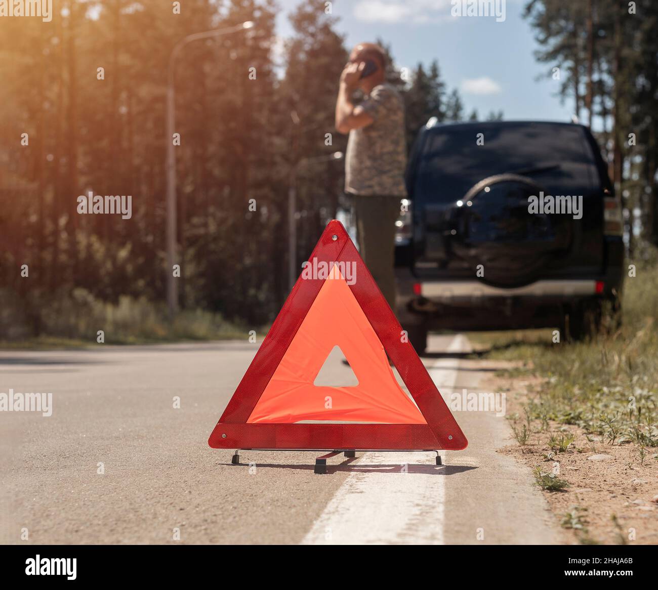 Triangle caution sign on road after car break and driver speaking on ...