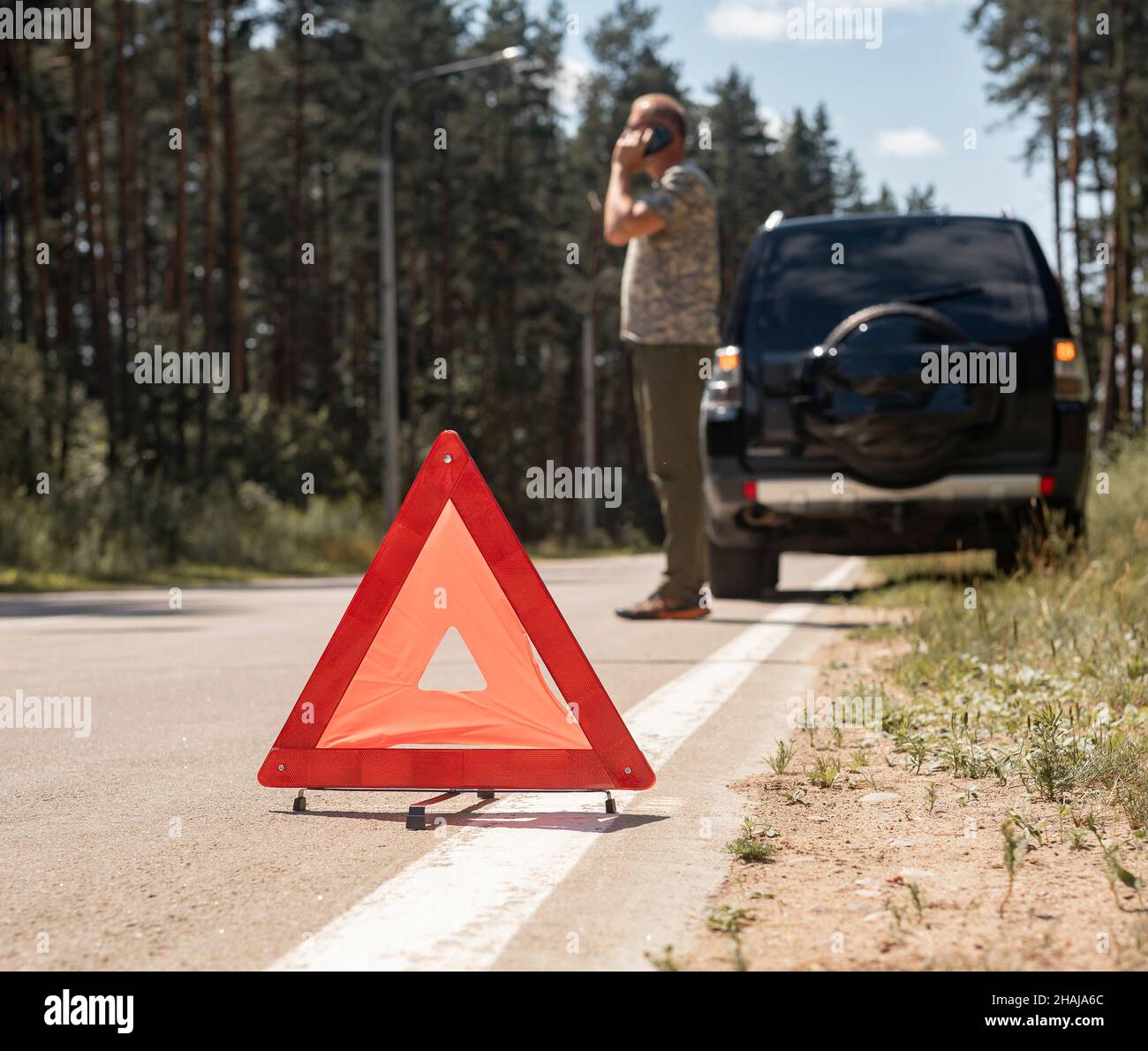 Triangle caution sign on road after car breakdown and driver talking on ...