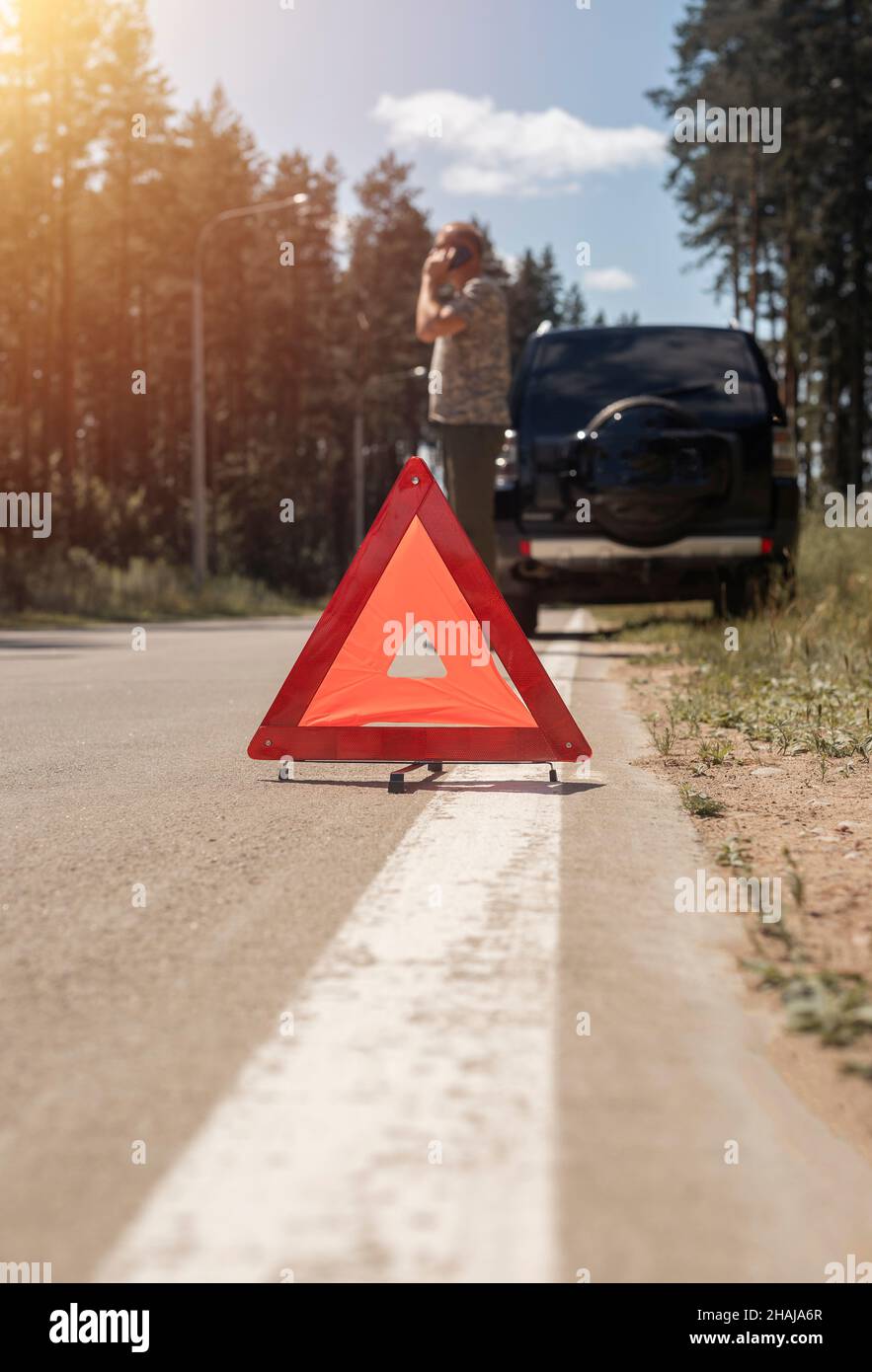 Triangle caution sign on road after car break and driver speaking on ...