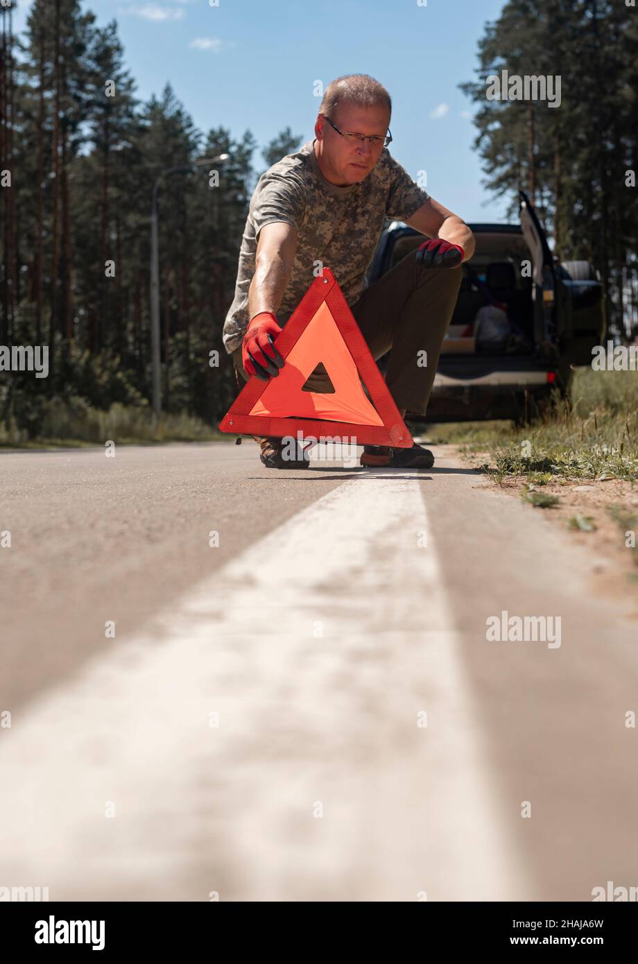 Man driver putting and setting red triangle caution warning sign on ...