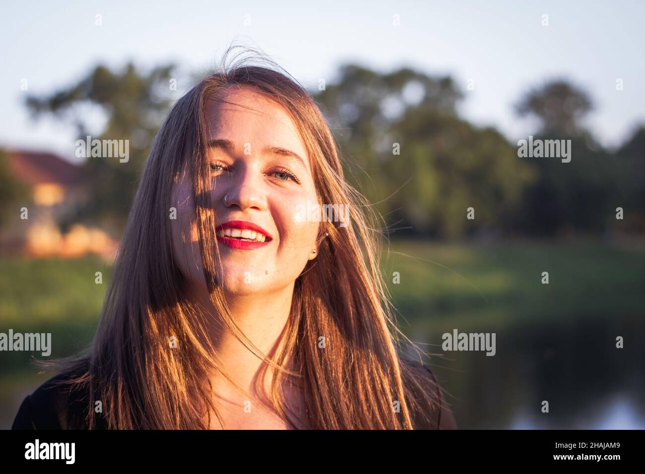 Portrait of young happy smiling woman enjoying sunset in city. Sunlight ...