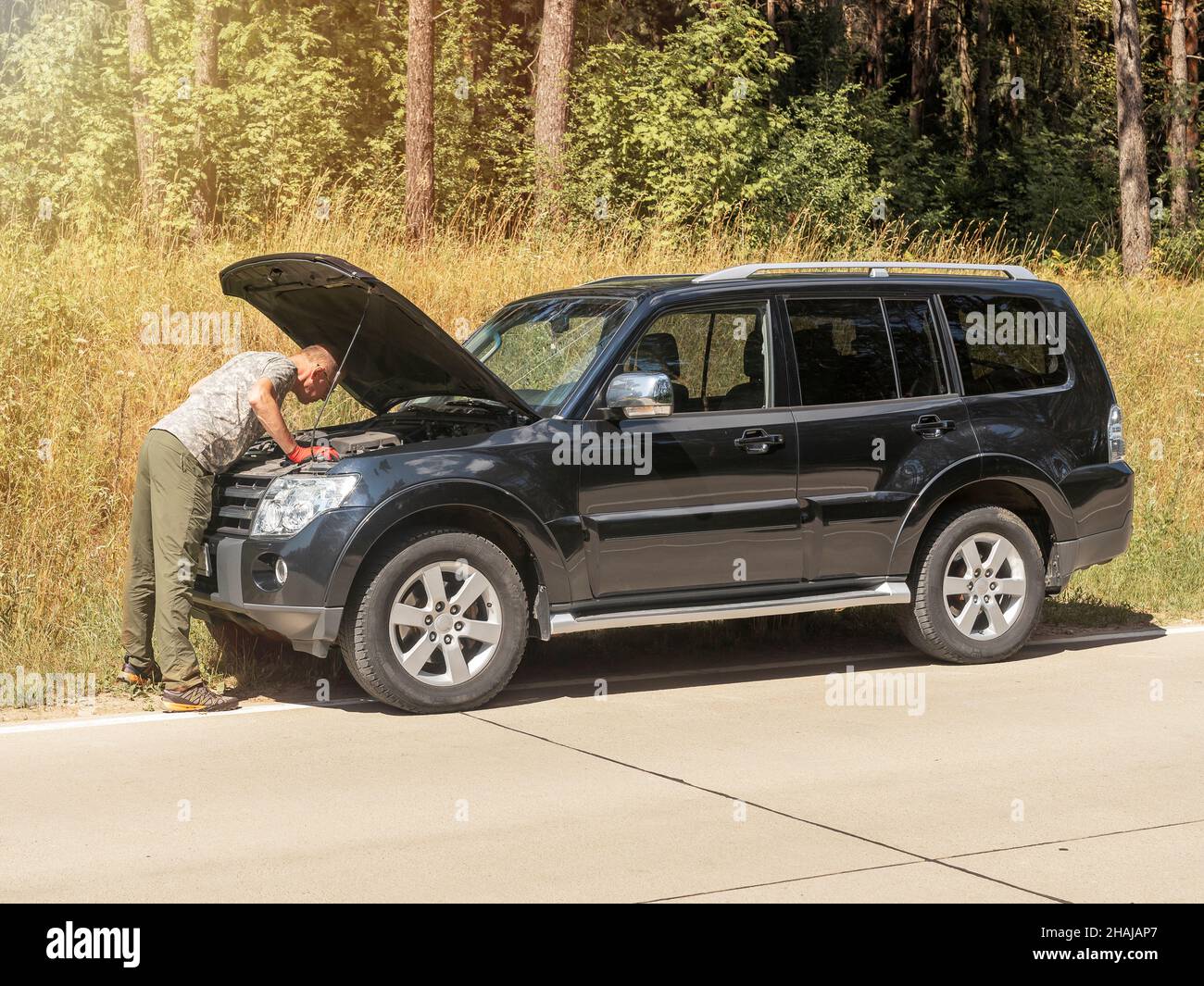 Man driver standing car hood raised up and checking for problems ...