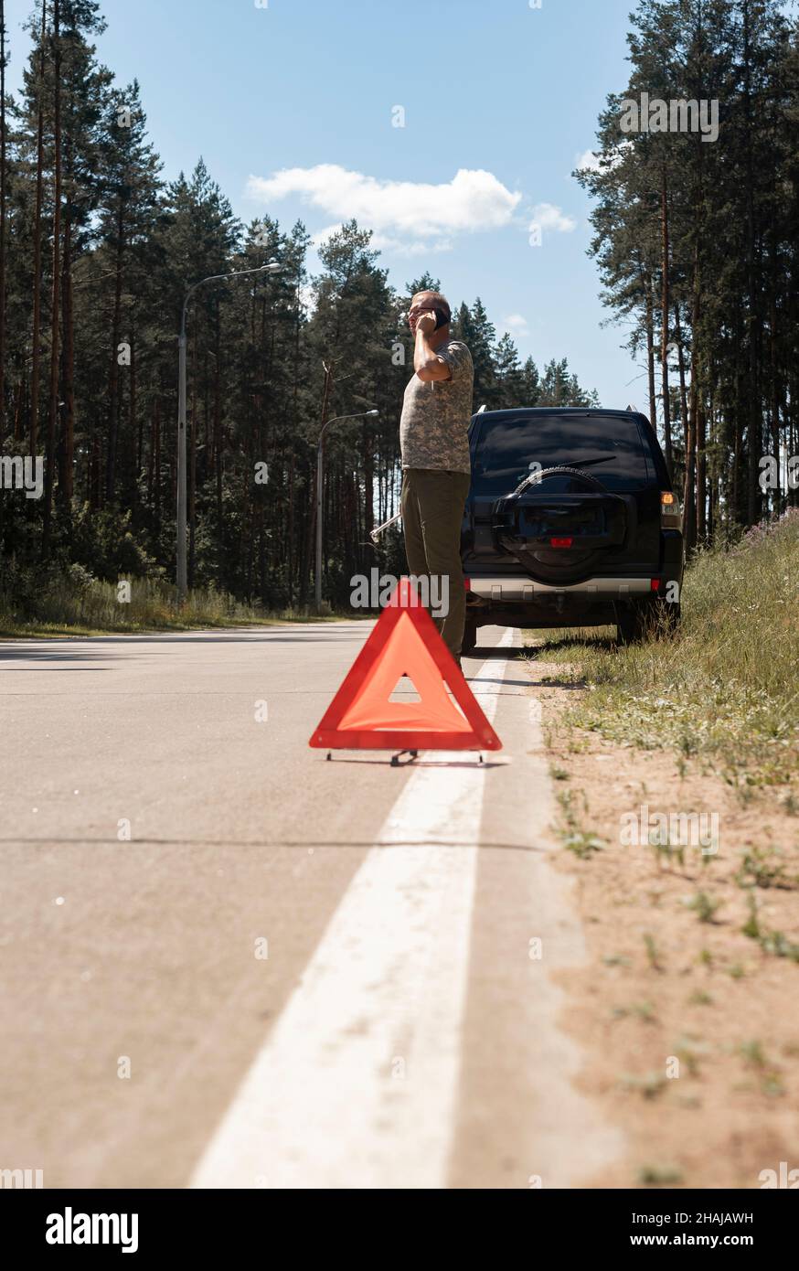 Red triangle sign on side road after car break and driver speaking on ...