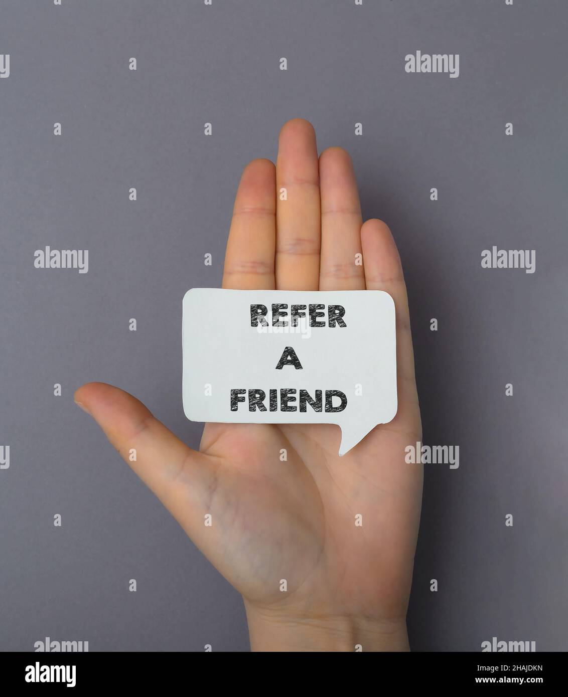 Refer a friend.Card with text in hand on a gray background. Referral ...