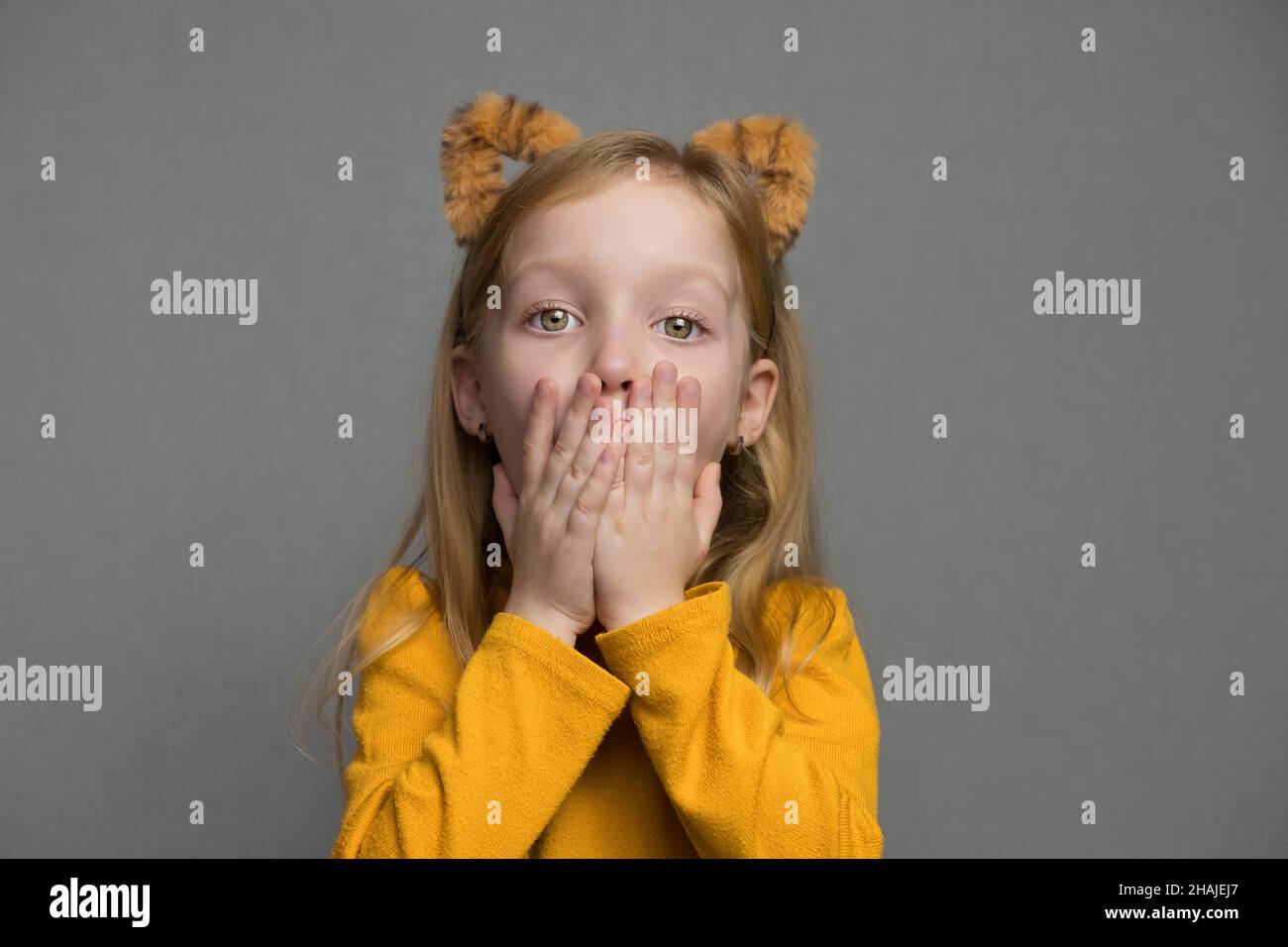 Cute surprised blond girl with tiger ears. A headdress with tiger ears ...