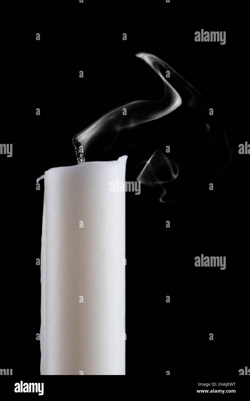 One candle with flame extinguished, smoke, on black background. Closeup ...