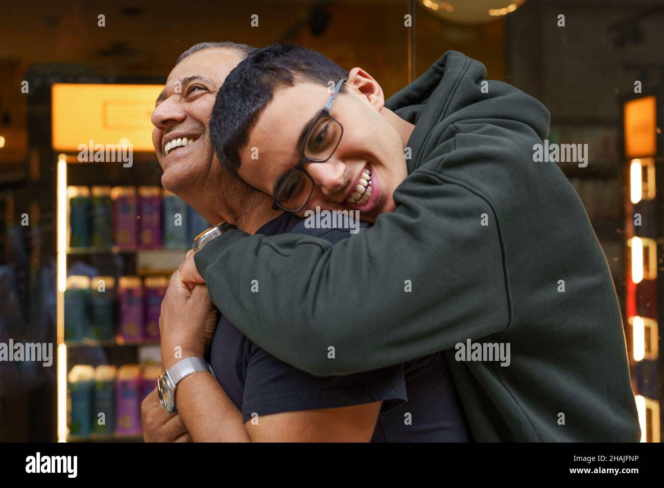 Hug for dad. A teen boy leans over to hug his father, who to be smiling ...