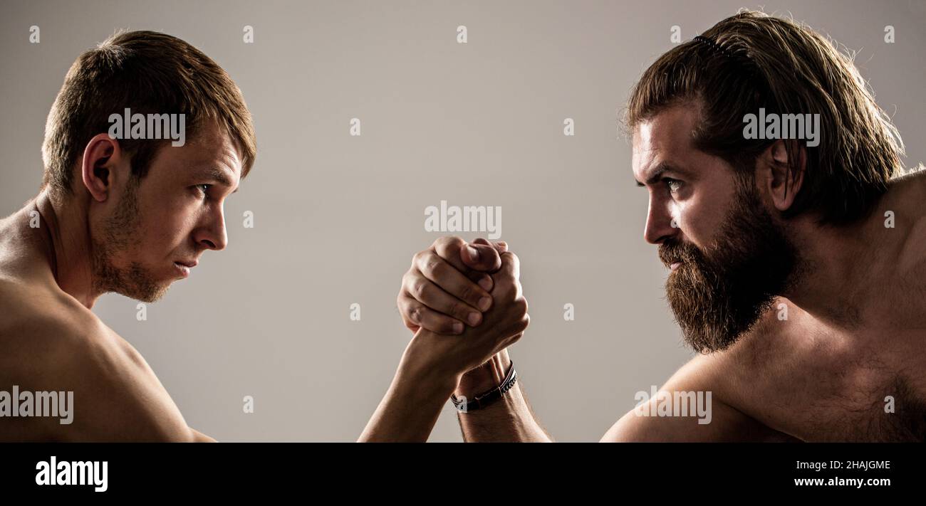 Arms wrestling thin hand, big strong arm in studio. Two man's hands ...