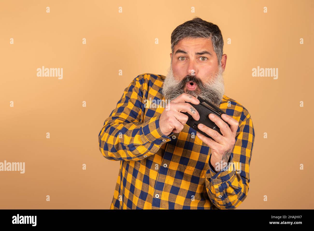 Handsome gamer with beard playing video game using joystick scared in ...