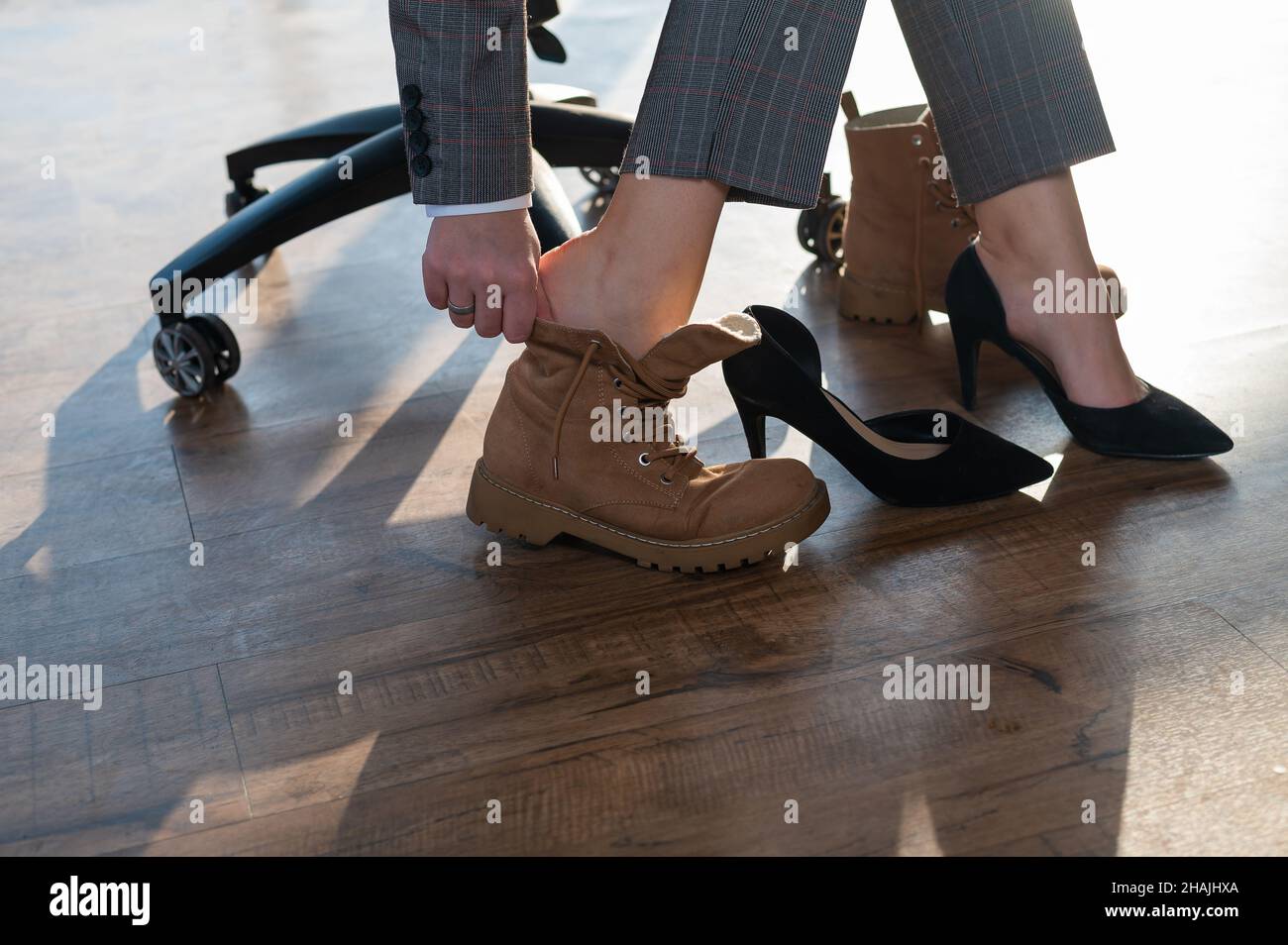 Business woman changes shoes with high heels on boots in the office ...