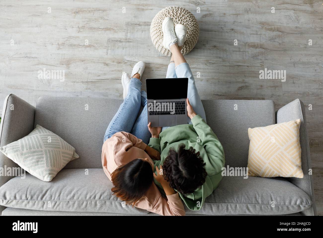 Top view of millennial Asian couple sitting on couch with laptop at ...