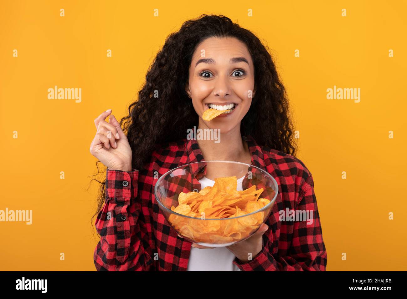 Excited Latin Lady Eating Delicious Potato Crisps Stock Photo - Alamy