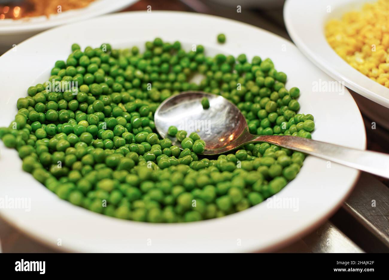 White porcelain plate with pile of cooked green peas displayed at food ...