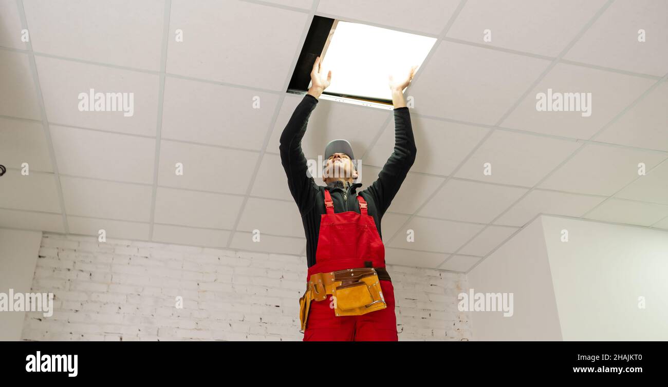 a builder replacing ceiling panel, working, armstrong Stock Photo - Alamy