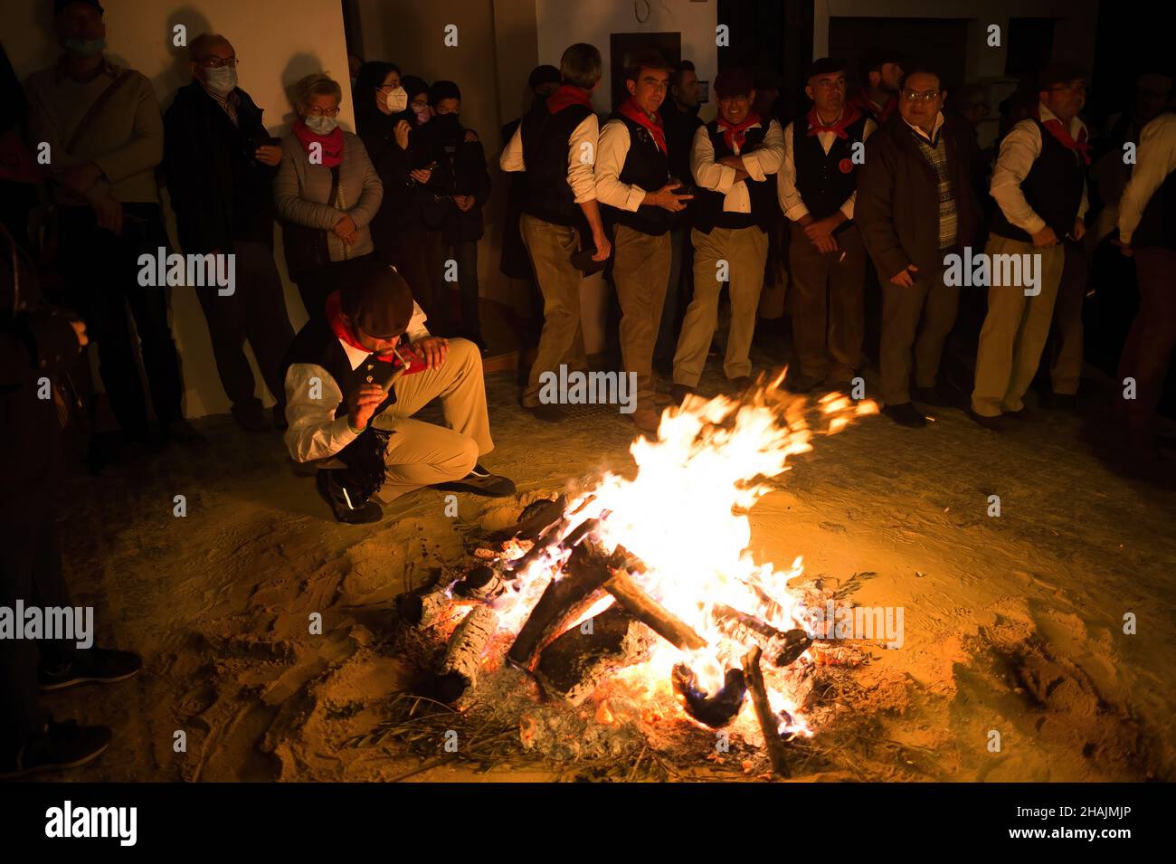 A villager is seen lighting a cigarette next to a bonfire as he takes ...