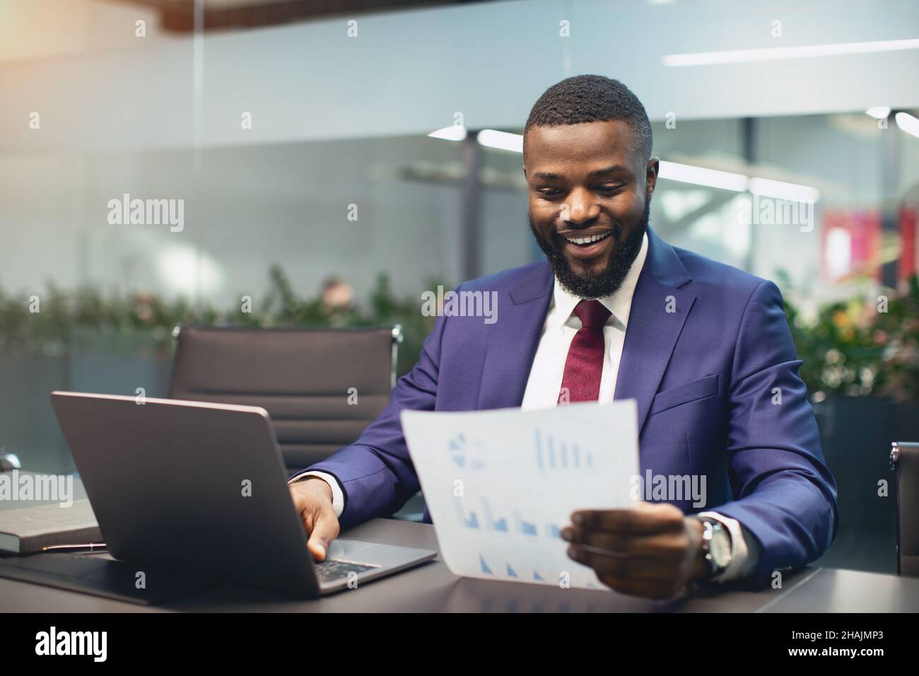 Smiling black businessman checking reports in modern office Stock Photo ...