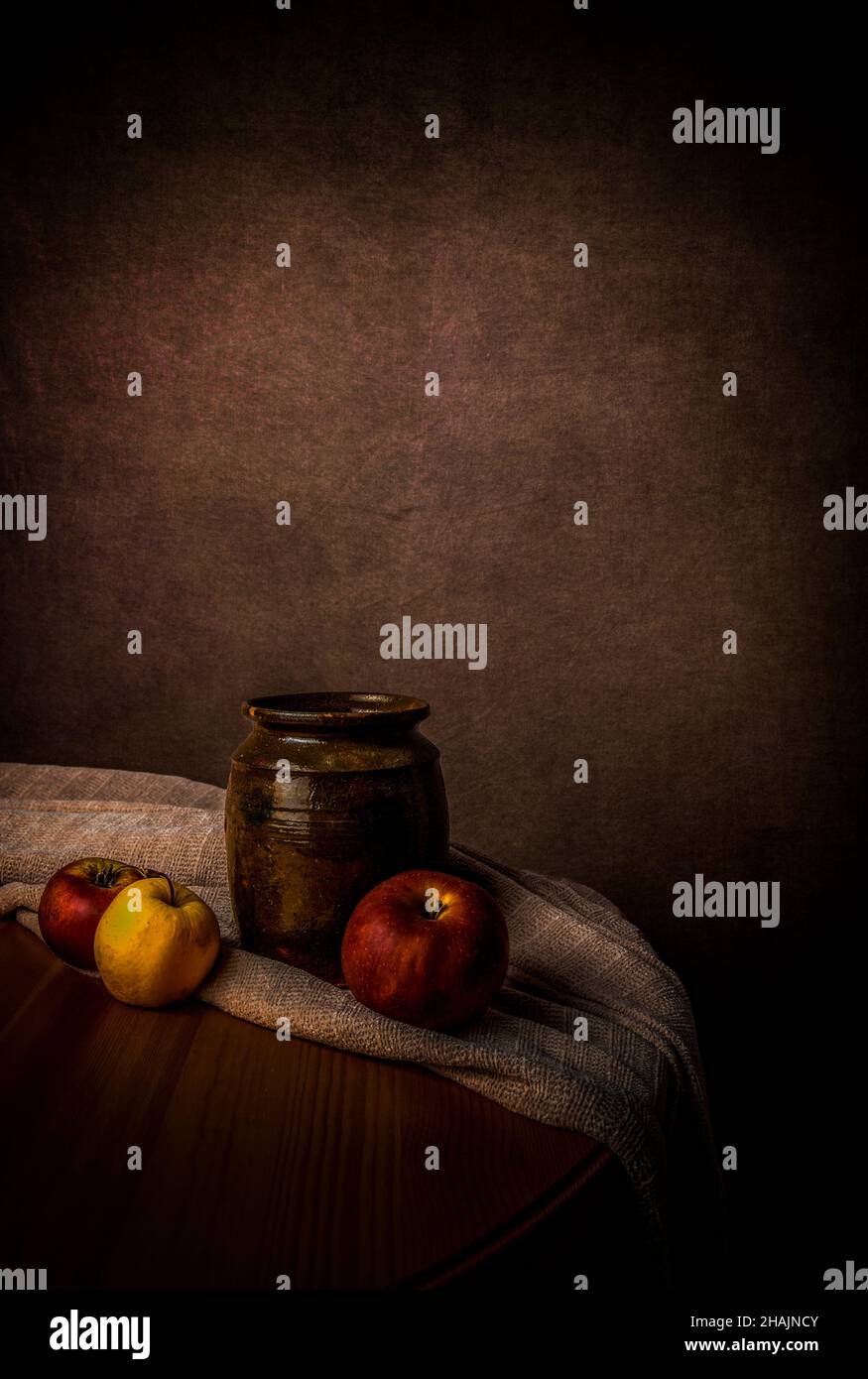 Still life with old water jar and three apples and a cloth on table ...
