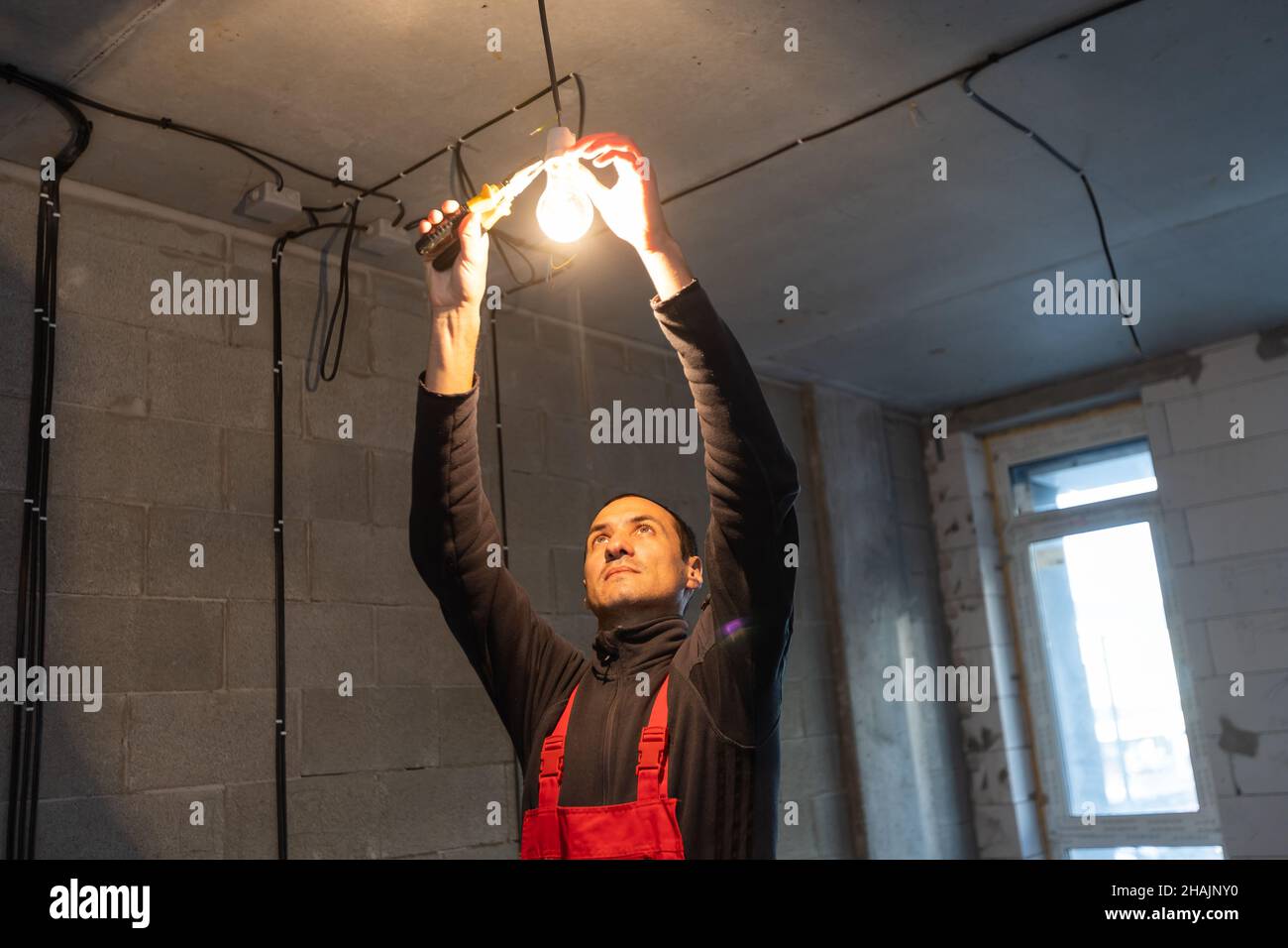 handsome young man electrician working on switchboard of house building ...