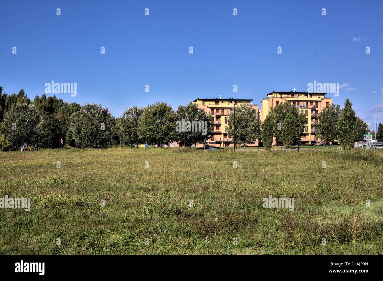 Field in the countryside with trees and residential buildings in the ...