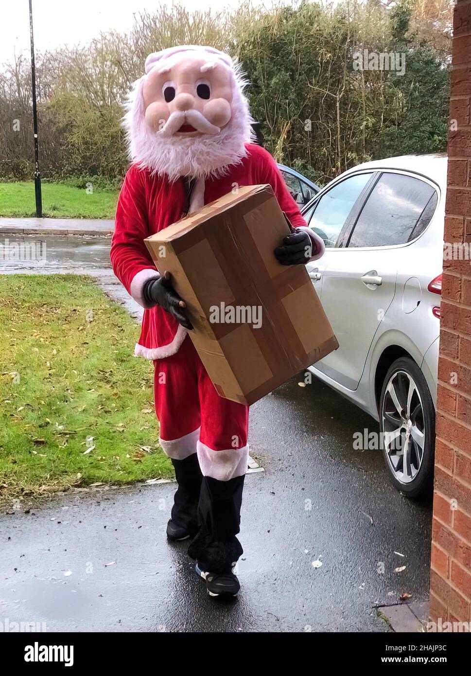Postman in a Santa Claus outfit delivering a parcel Stock Photo - Alamy