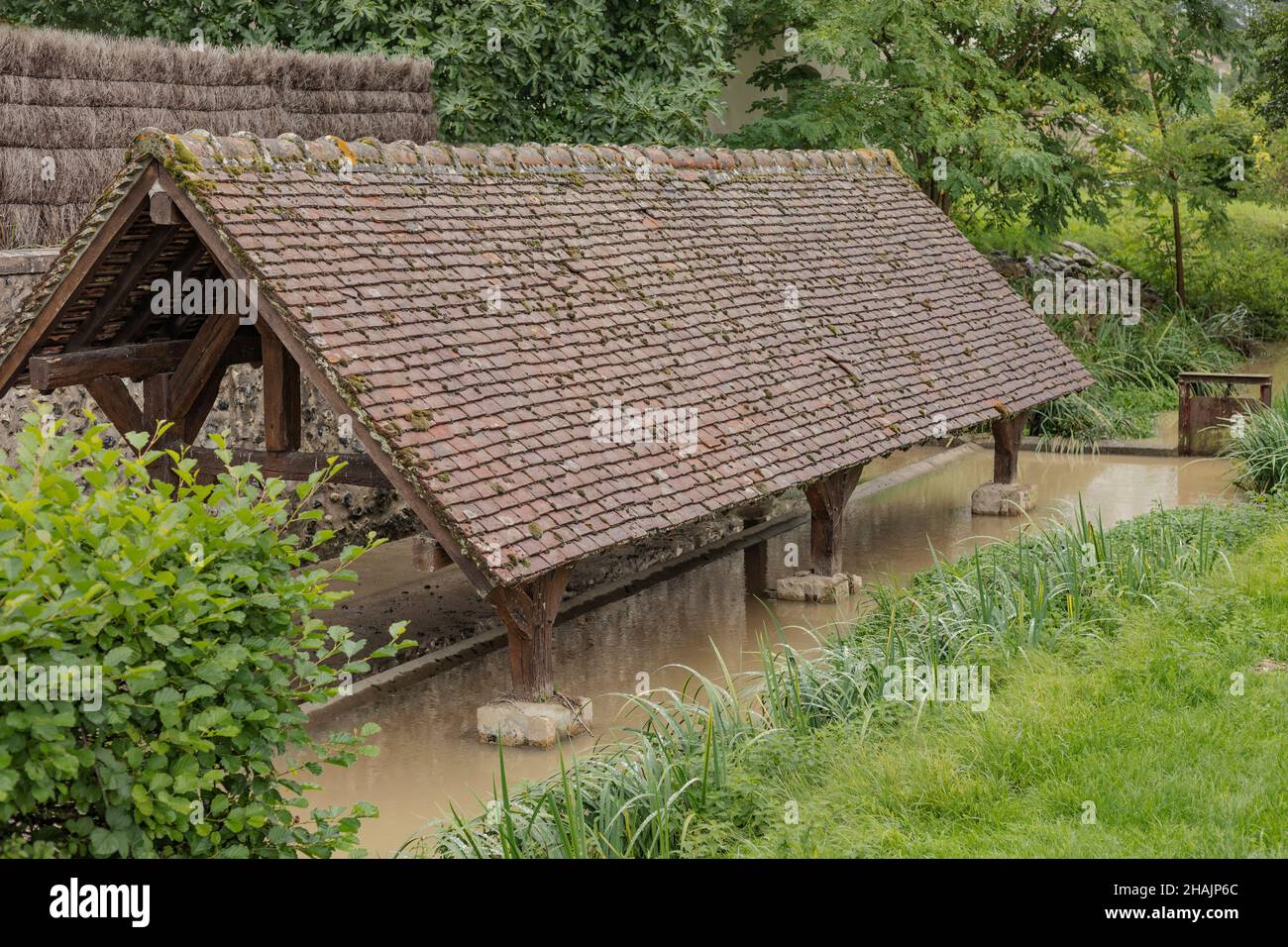 Wash house with tiled roof near to a stream with water standing ...