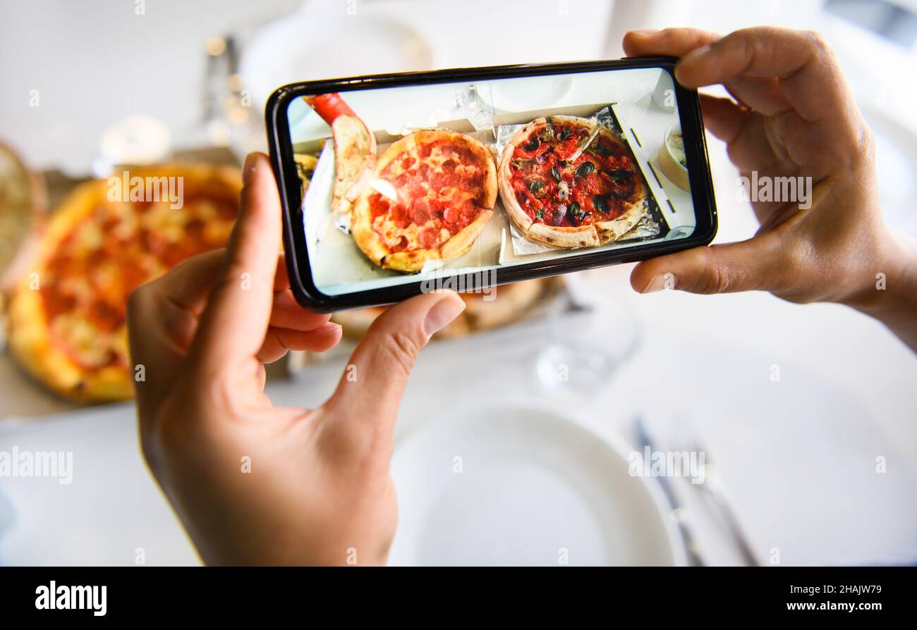 Hands holding mobile phone and taking image of delicious freshly baked ...