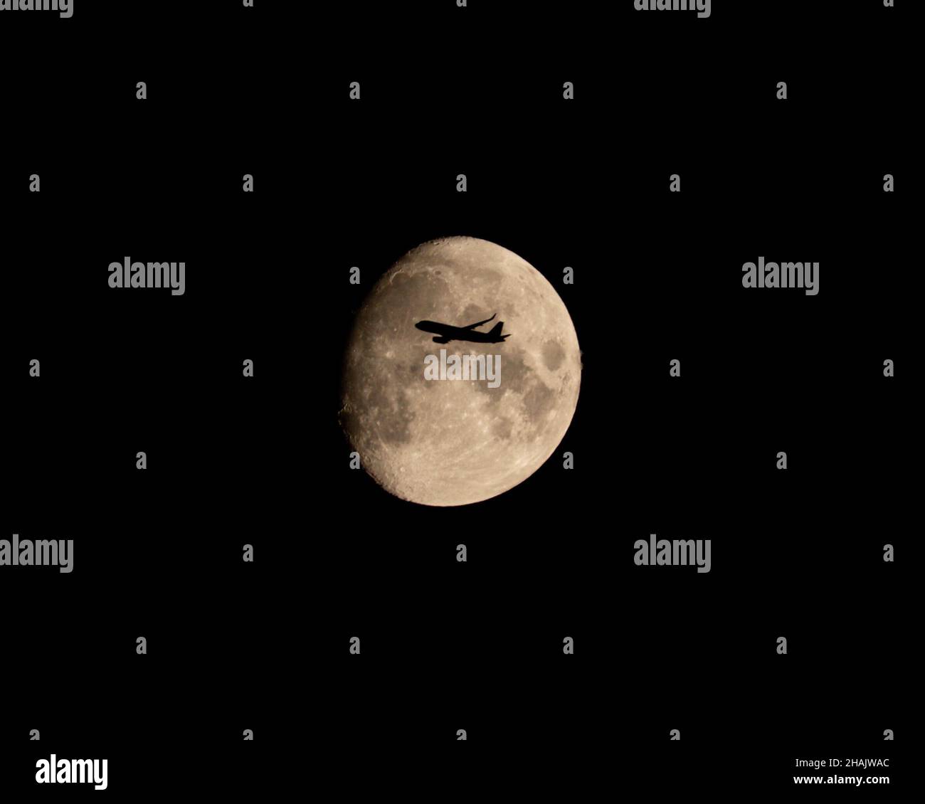 Silhouette of the flying plane against the full moon in the night sky ...