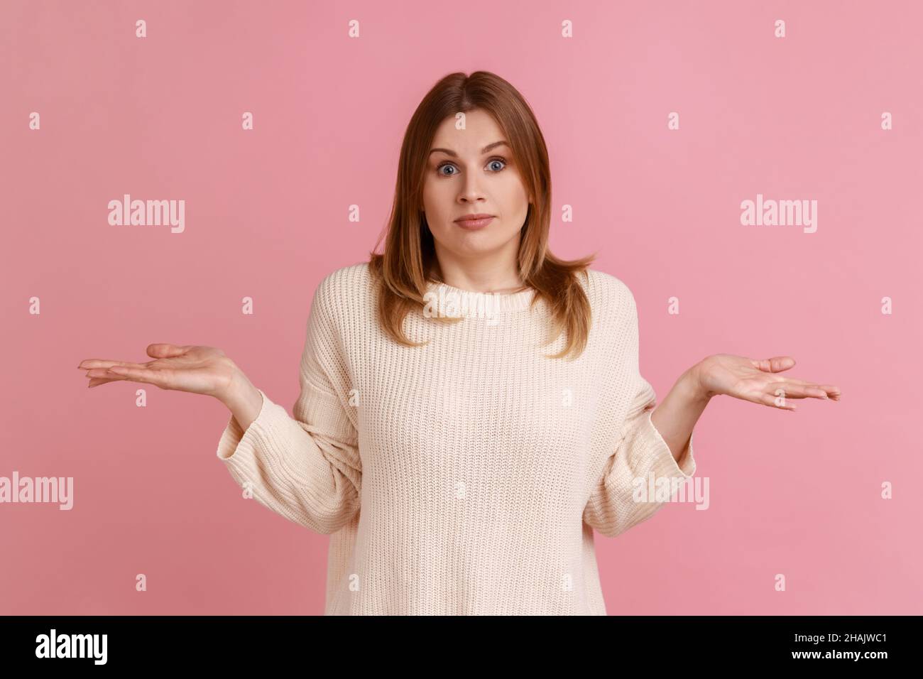 Portrait of confused blond woman standing with raised arms and looking ...