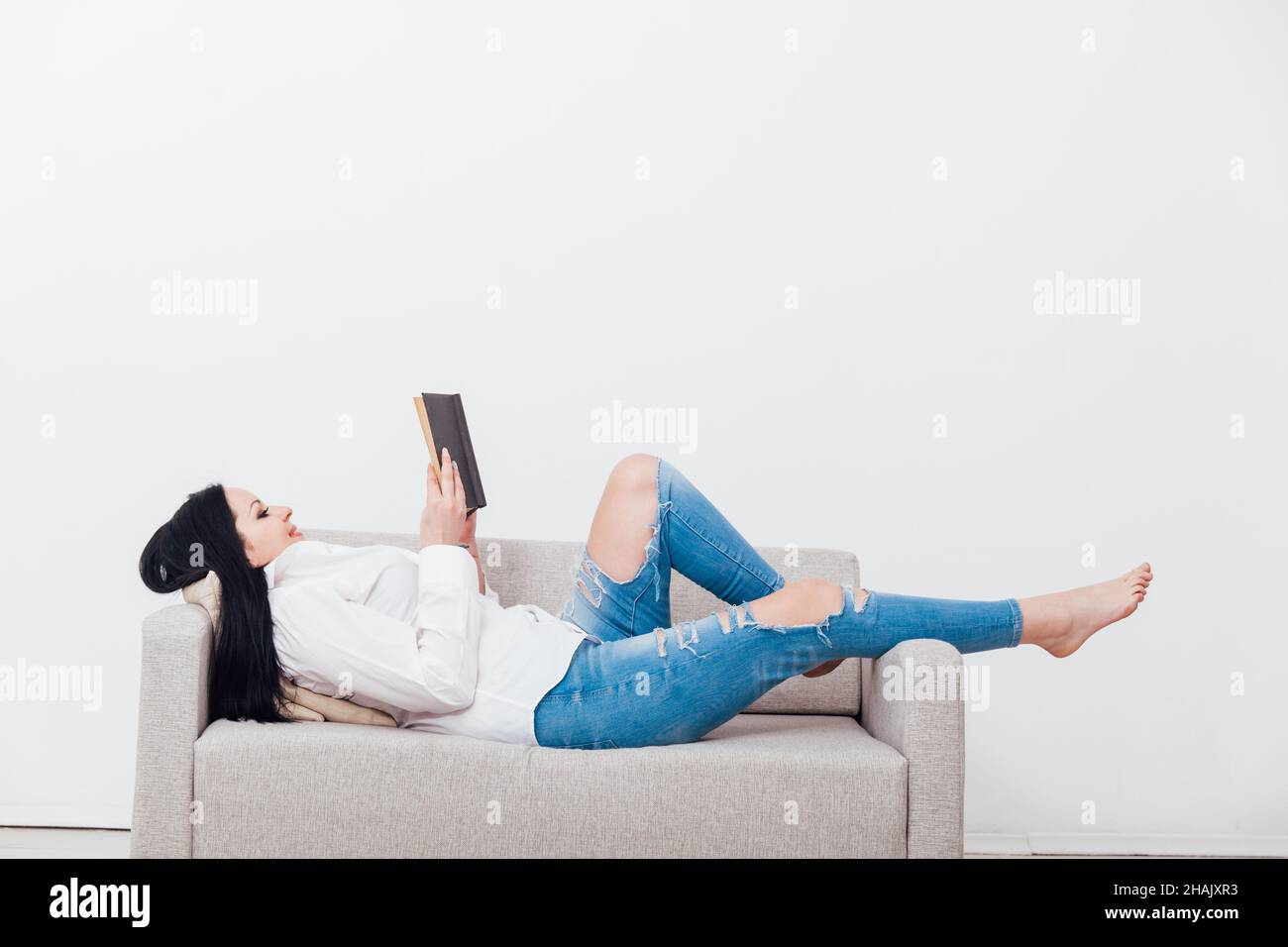 beautiful brunette woman in home clothes on the couch Stock Photo - Alamy