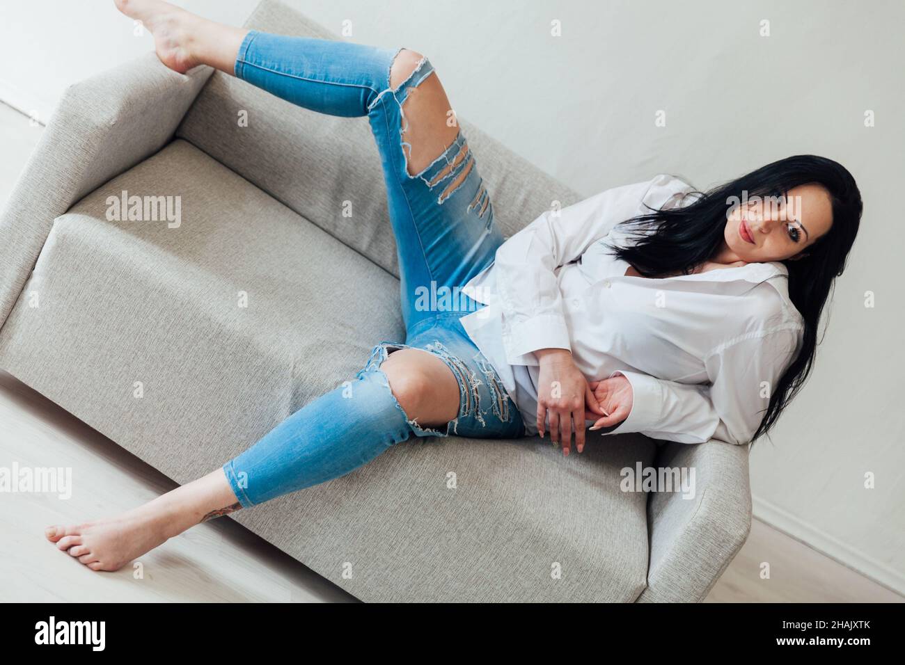 beautiful brunette woman in home clothes on the couch Stock Photo - Alamy