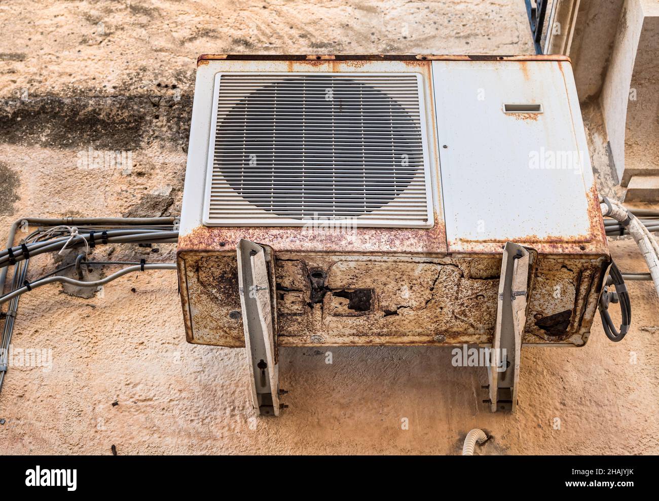 Old external air conditioner device hung on the stone wall of the ...