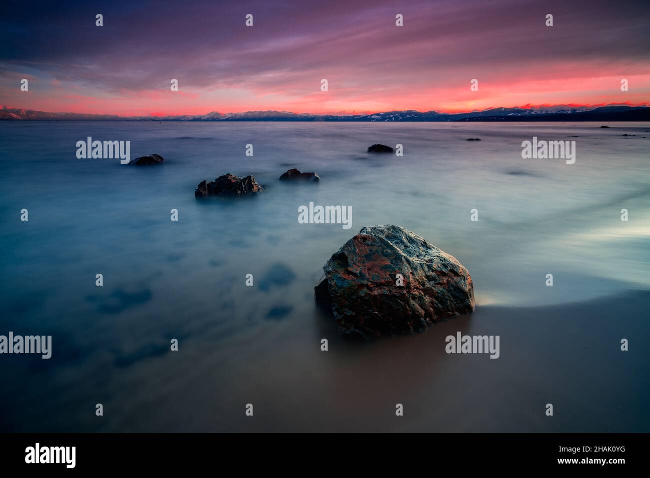 Long exposure shot rocks at sea with a beautiful sunset sky in the ...