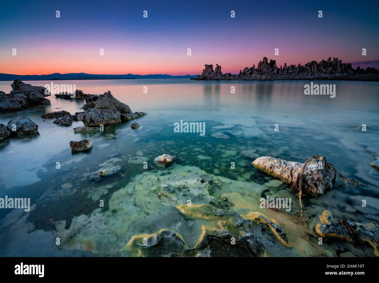 Long exposure shot rocks at sea with a beautiful sunset sky in the ...