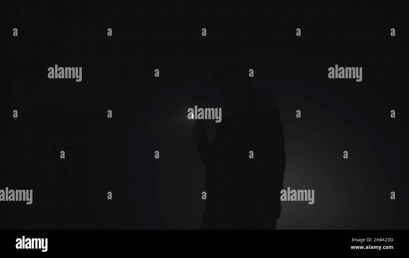 Silhouette of man shining with flashlight in the dark. Silhouette of ...
