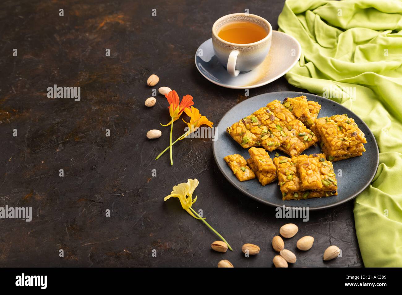 Traditional iranian dessert sohan with cup of green tea on a black ...