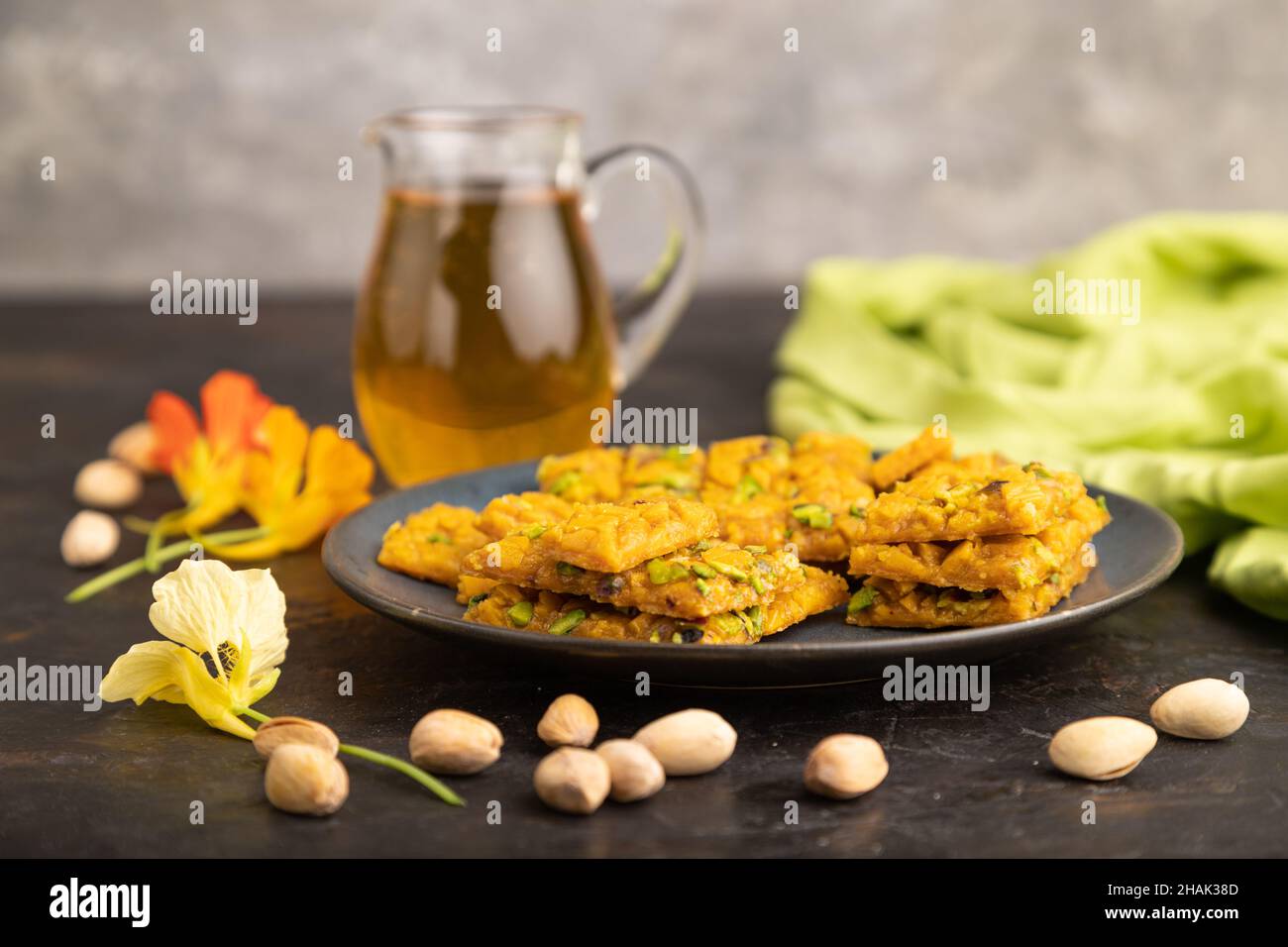 Traditional iranian dessert sohan with glass of green tea on a black ...